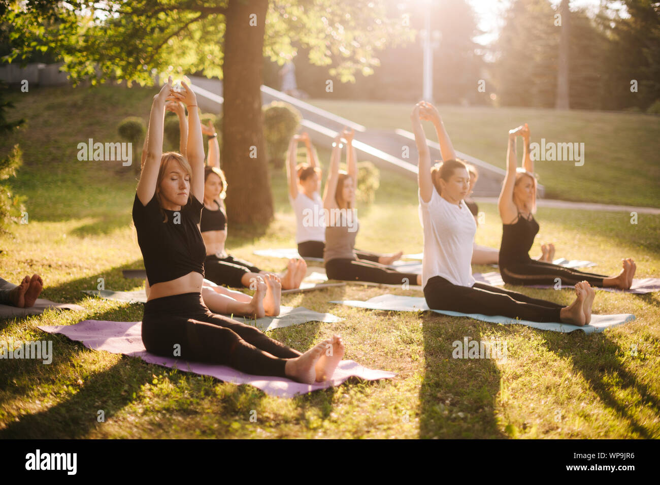 Group of women are practicing yoga and raising hands above heads at ...