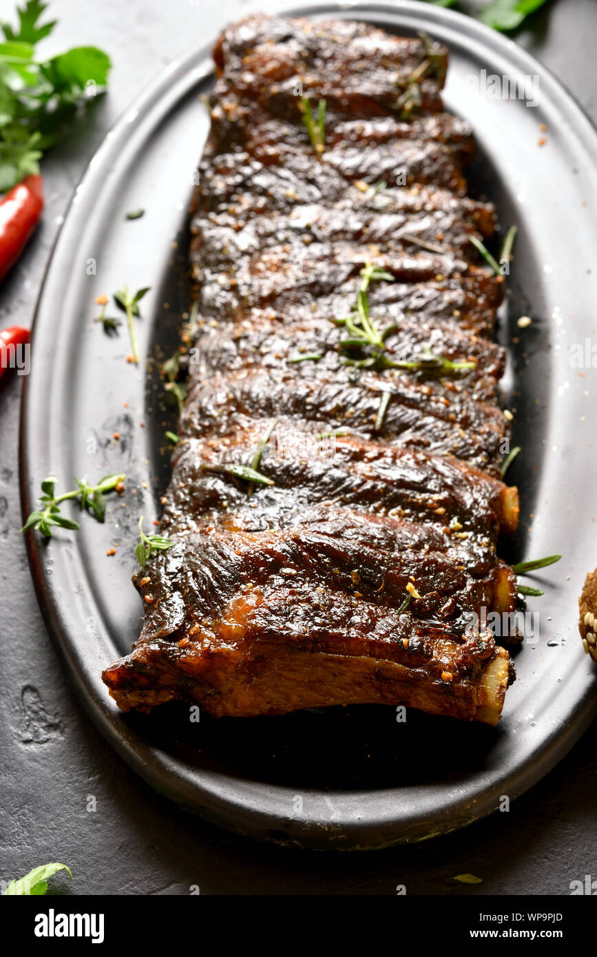 Close up of hot grilled spare ribs on plate over black stone background ...