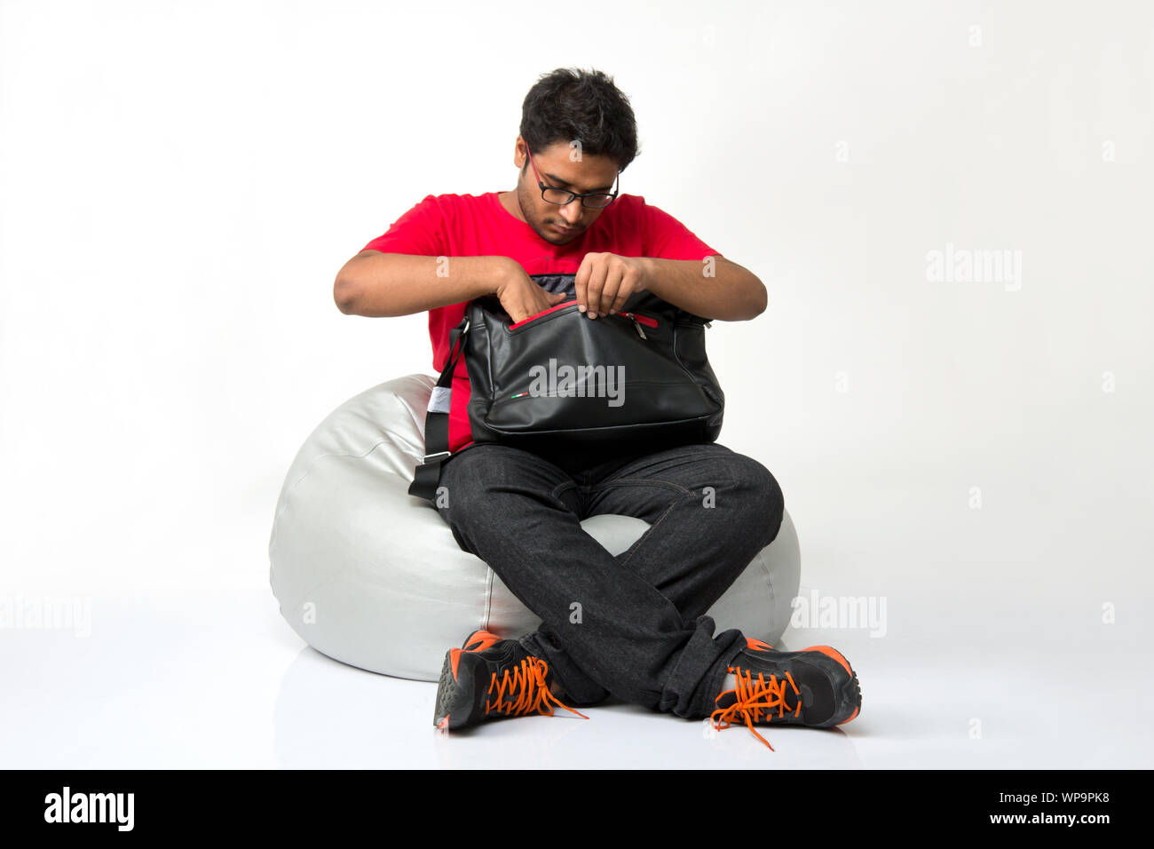 Young man searching in his bag Stock Photo - Alamy