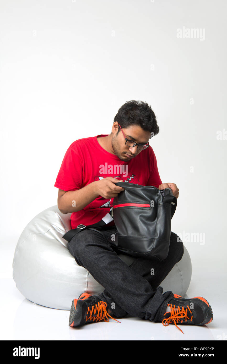 Young man searching in his bag Stock Photo - Alamy
