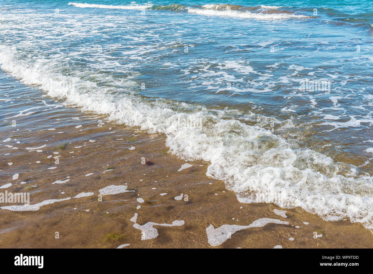 Sea shore with small waves Stock Photo - Alamy