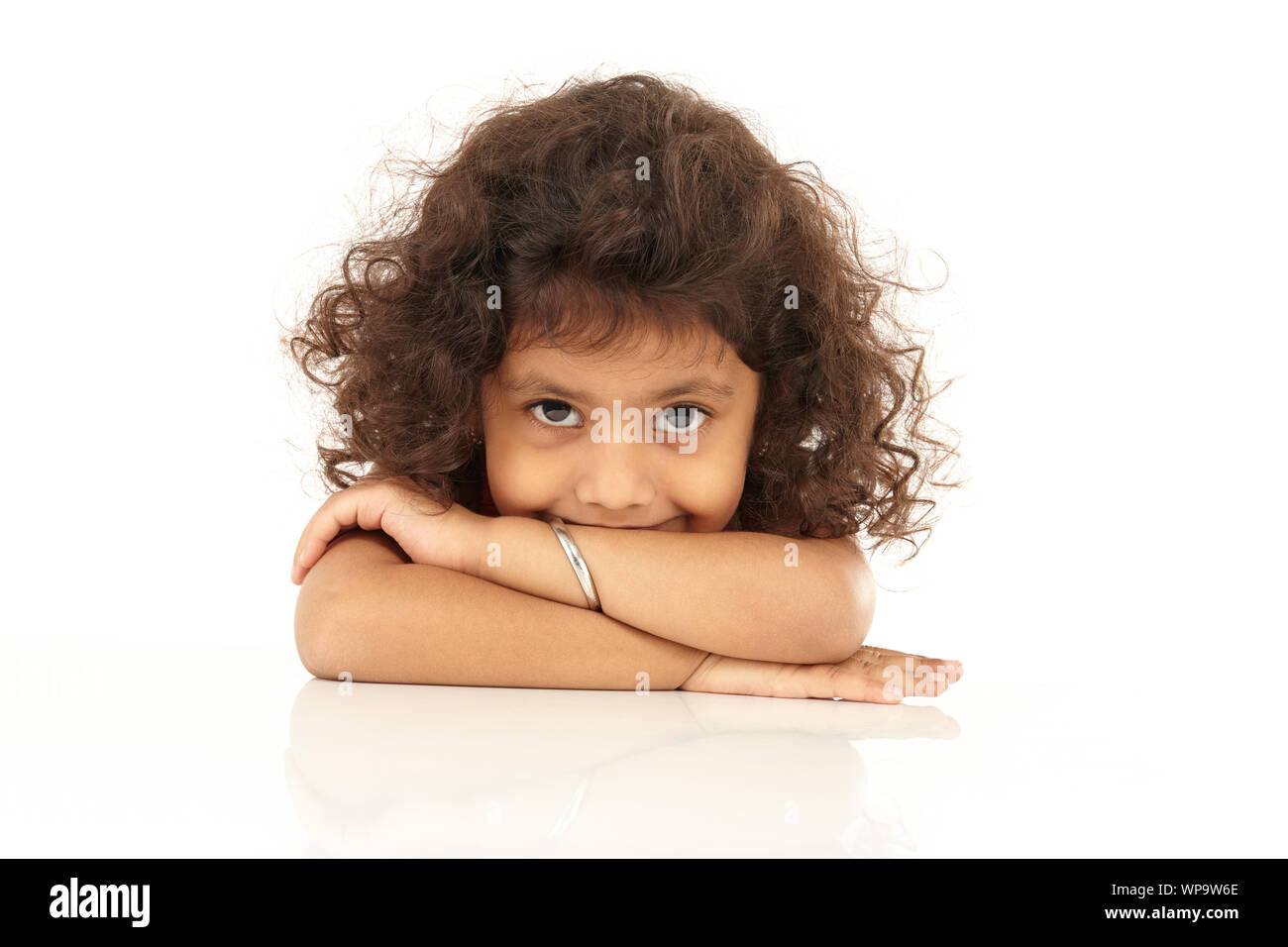 Girl resting head on arms at table Stock Photo - Alamy