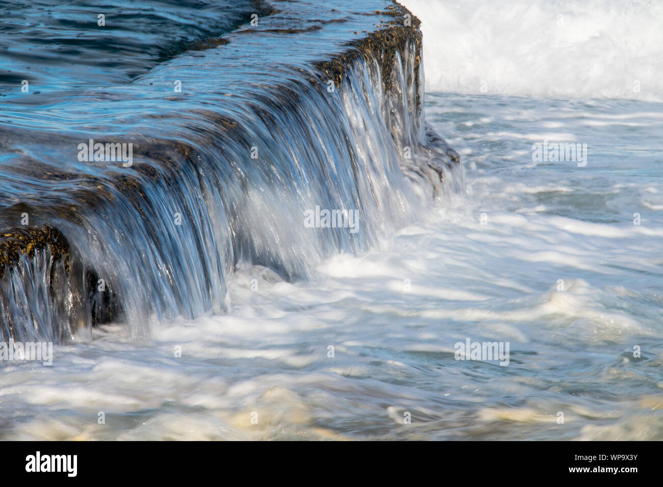 Strong afternoon, incoming tide with waves crashing on a tidal pool ...