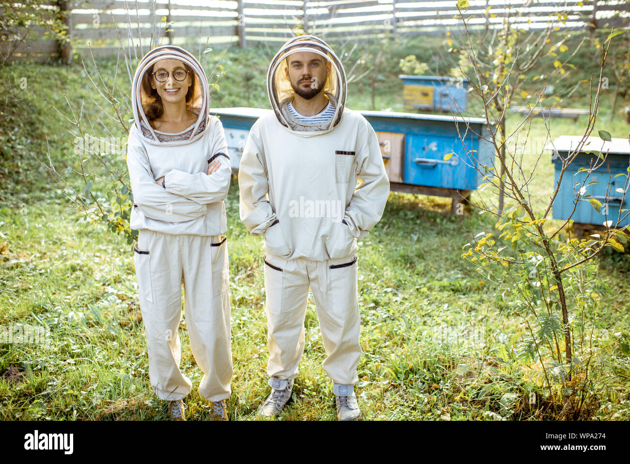 Portrait of a man and woman apiarists in protective uniform standing on ...