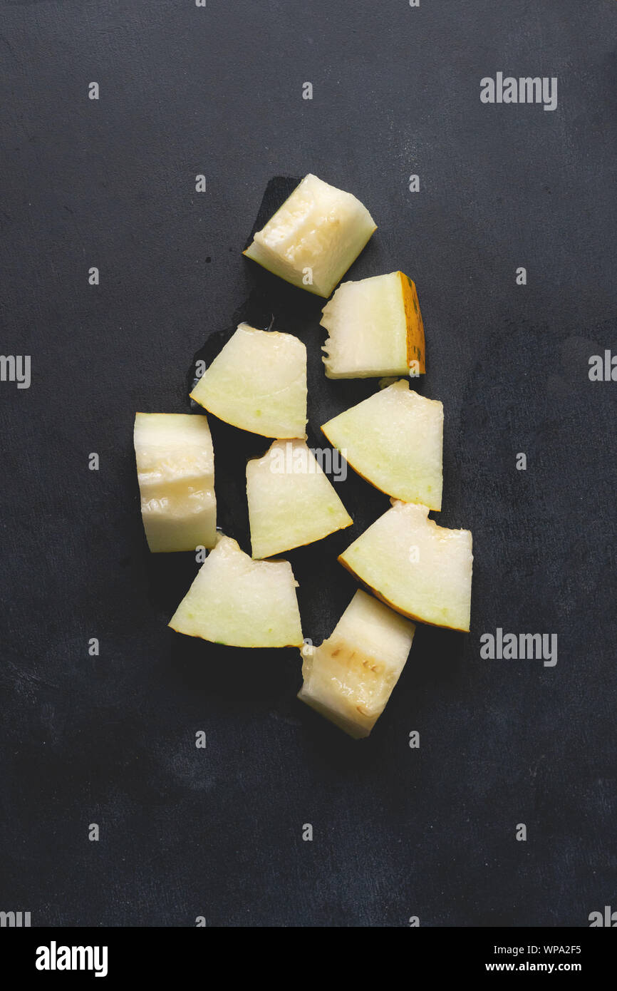 top view of fesh melon sliced pieces, cut on black surface Stock Photo ...