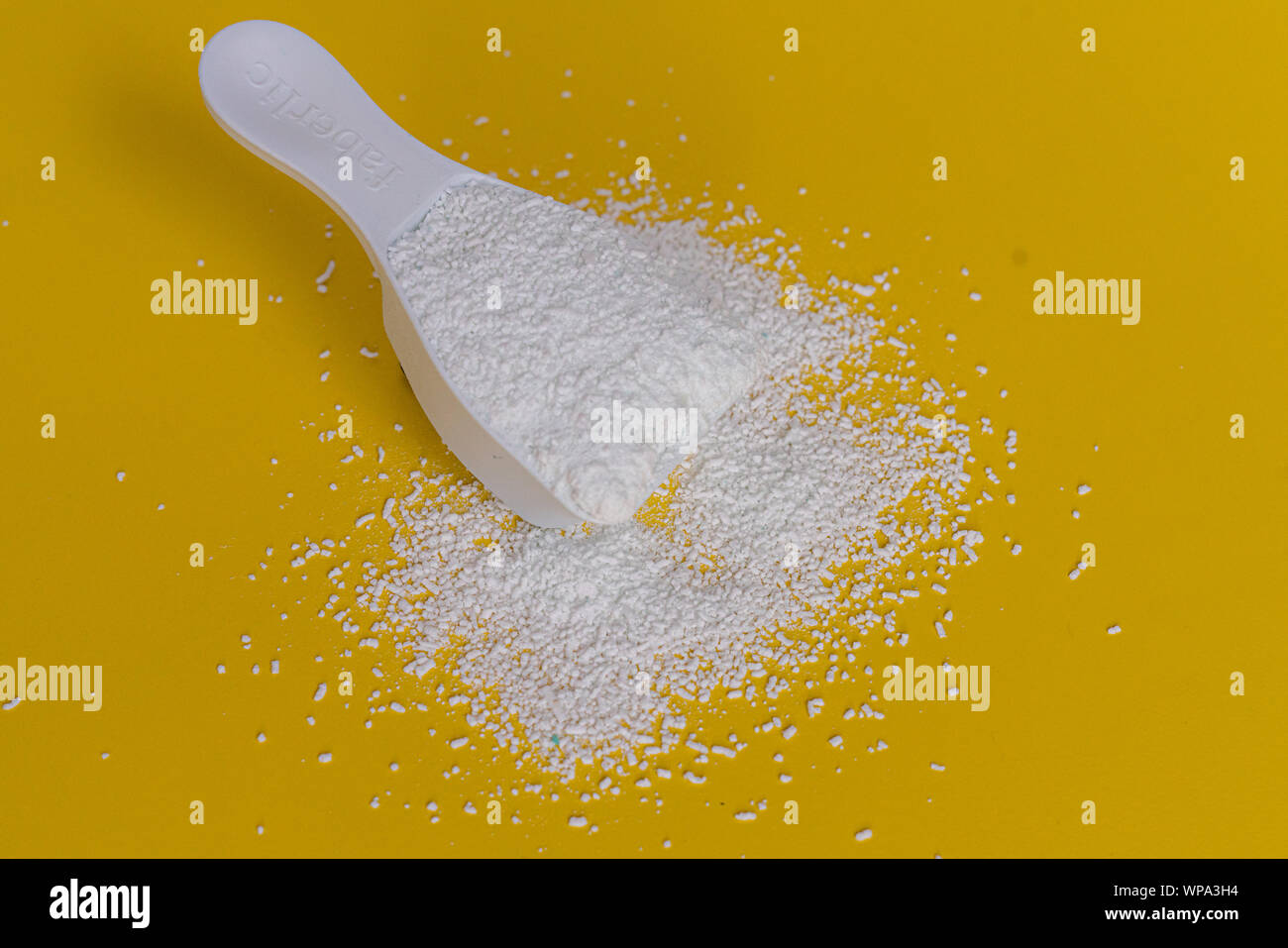 little scoop with washing powder detergent on the yellow surface s ...