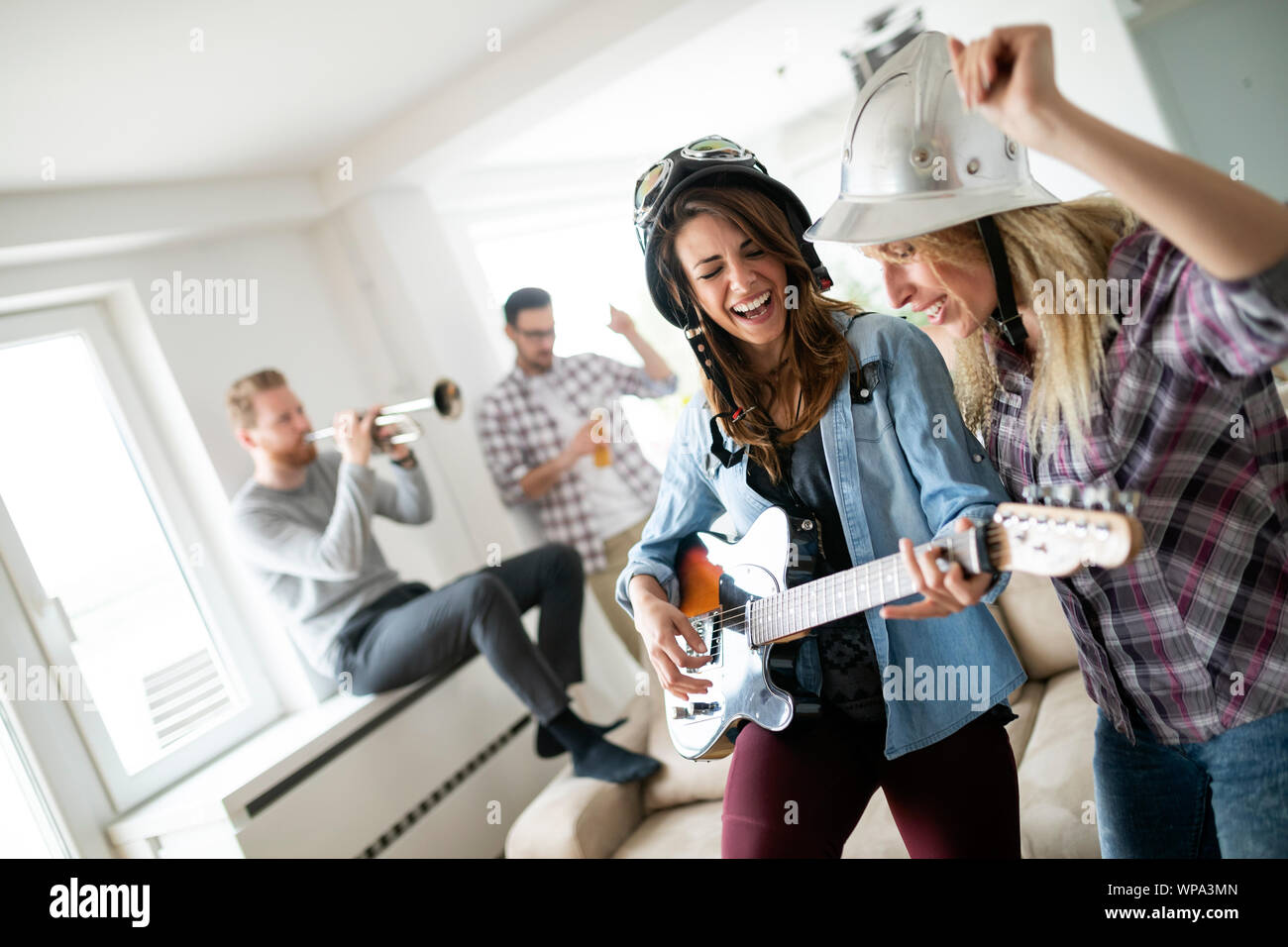 Group of young friends having fun together and playing in music band ...