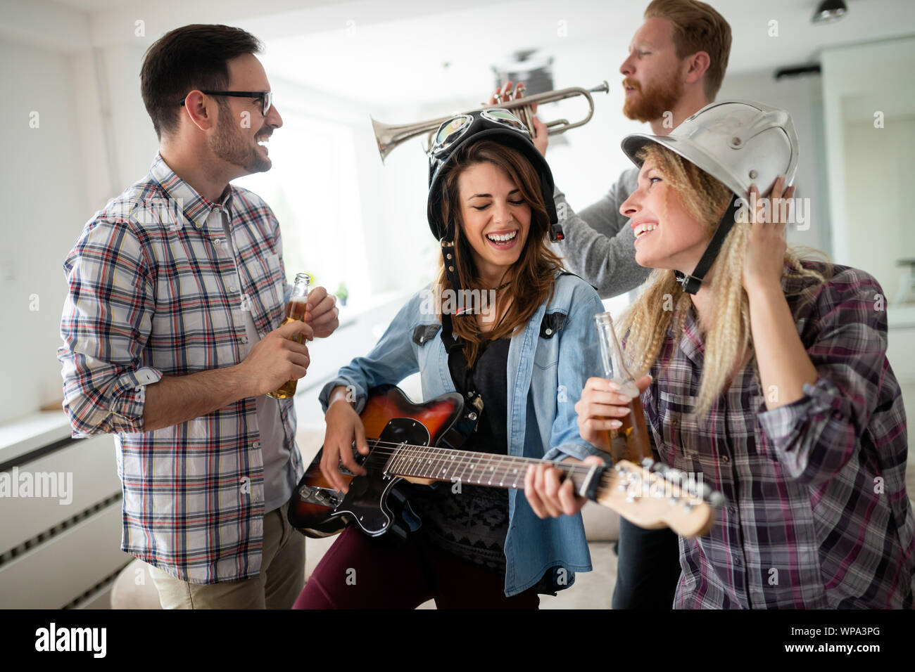 Group of young friends having fun together and playing in music band ...