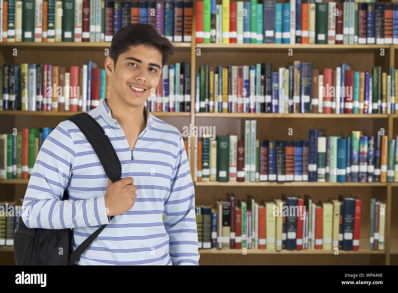 College student carrying a backpack in a library Stock Photo - Alamy