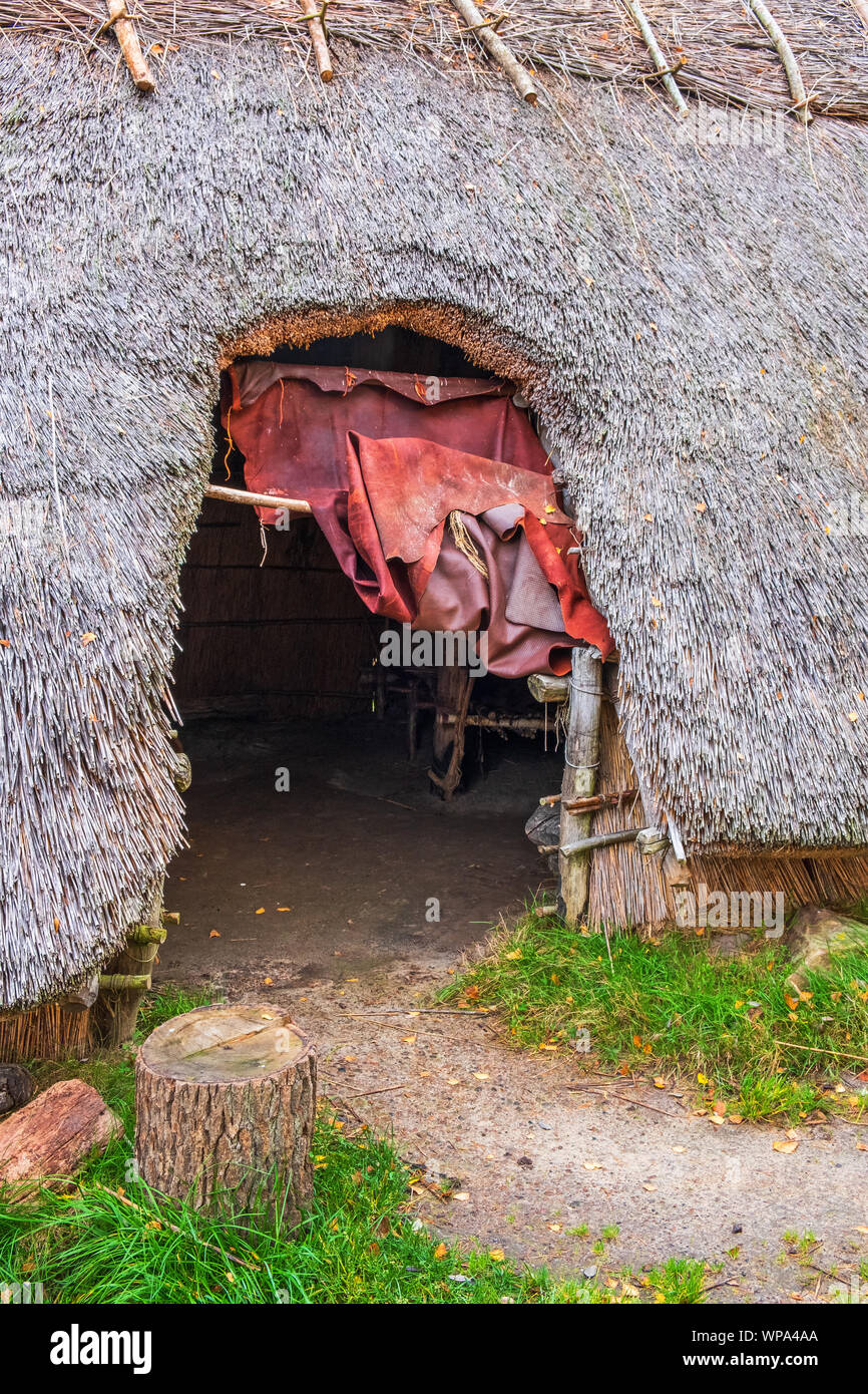 Opening at a reconstructed straw hut from prehistoric era with a animal ...