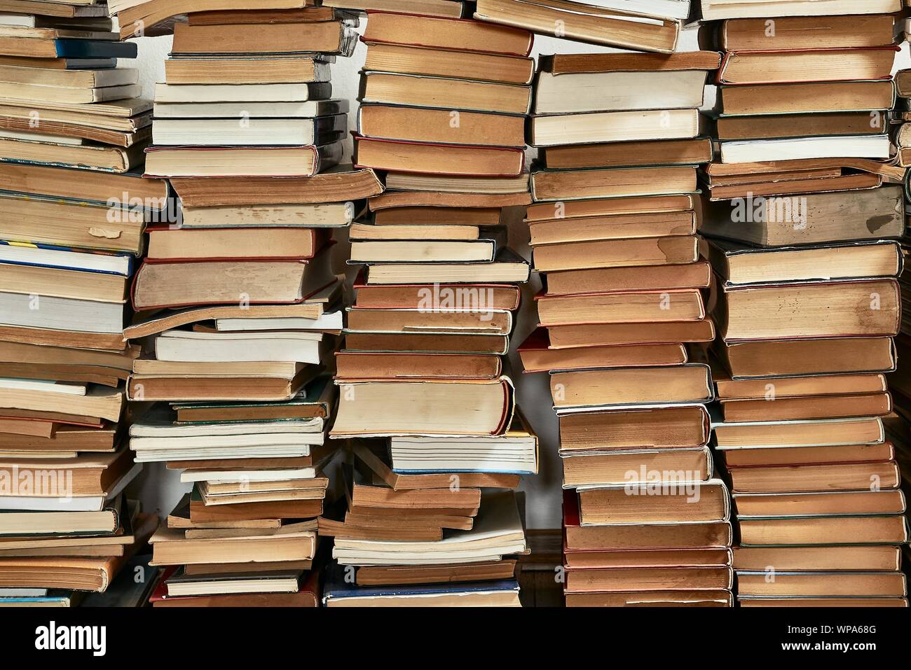 Wall of books piled up Stock Photo - Alamy