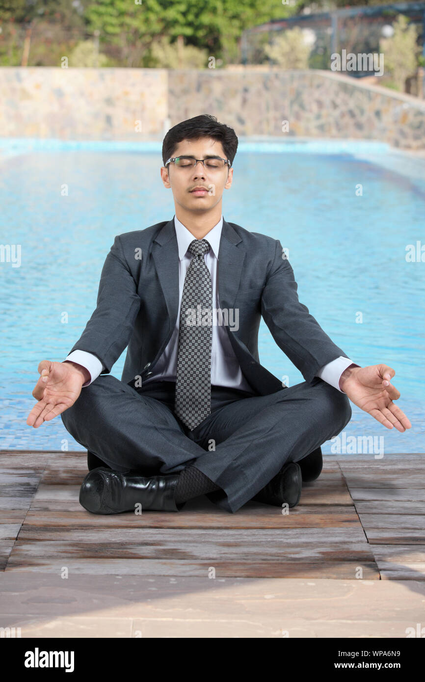 Businessman sitting in yoga pose at poolside Stock Photo - Alamy