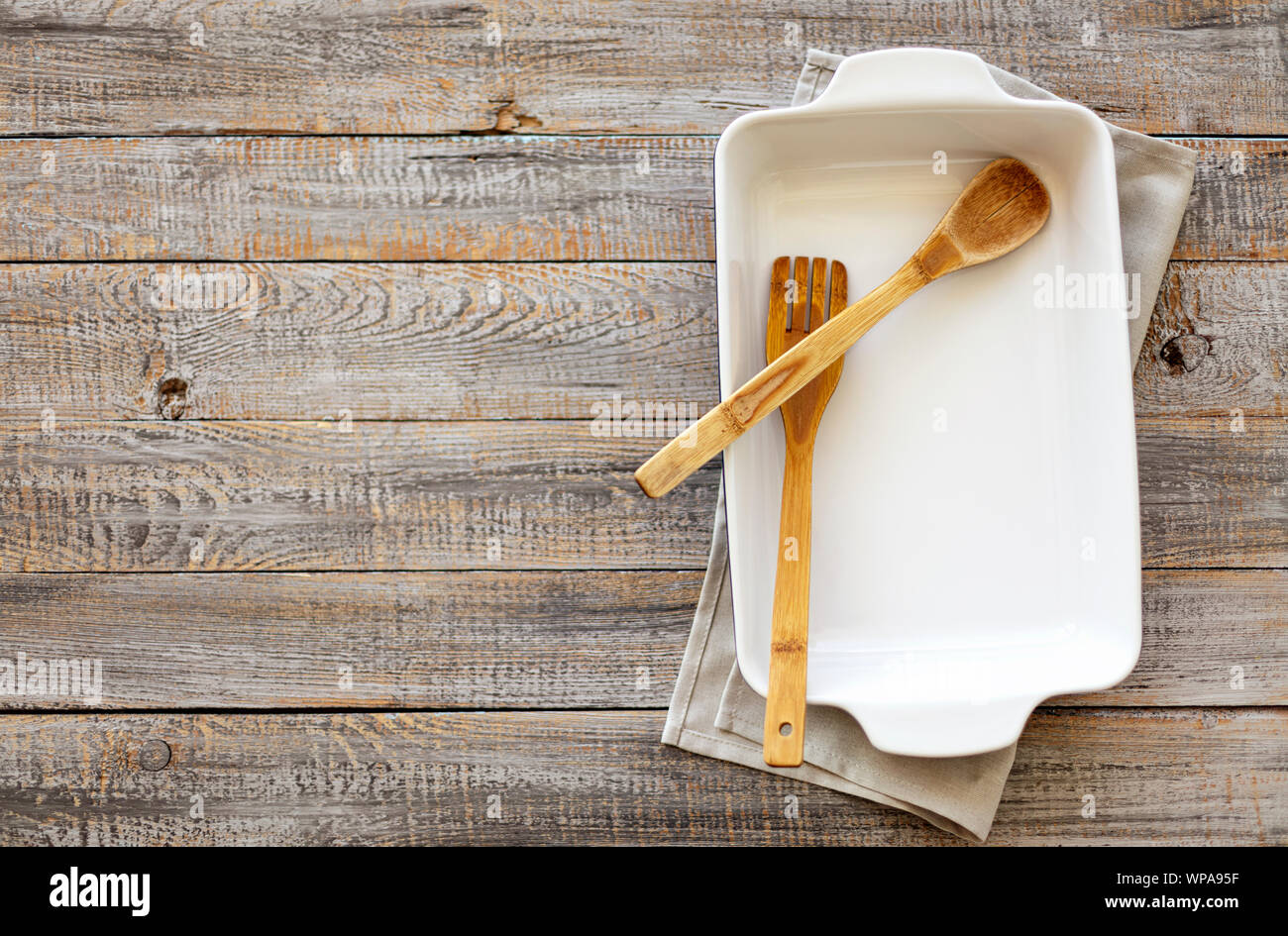Ceramic white baking dish on a wooden old background. Selective focus ...