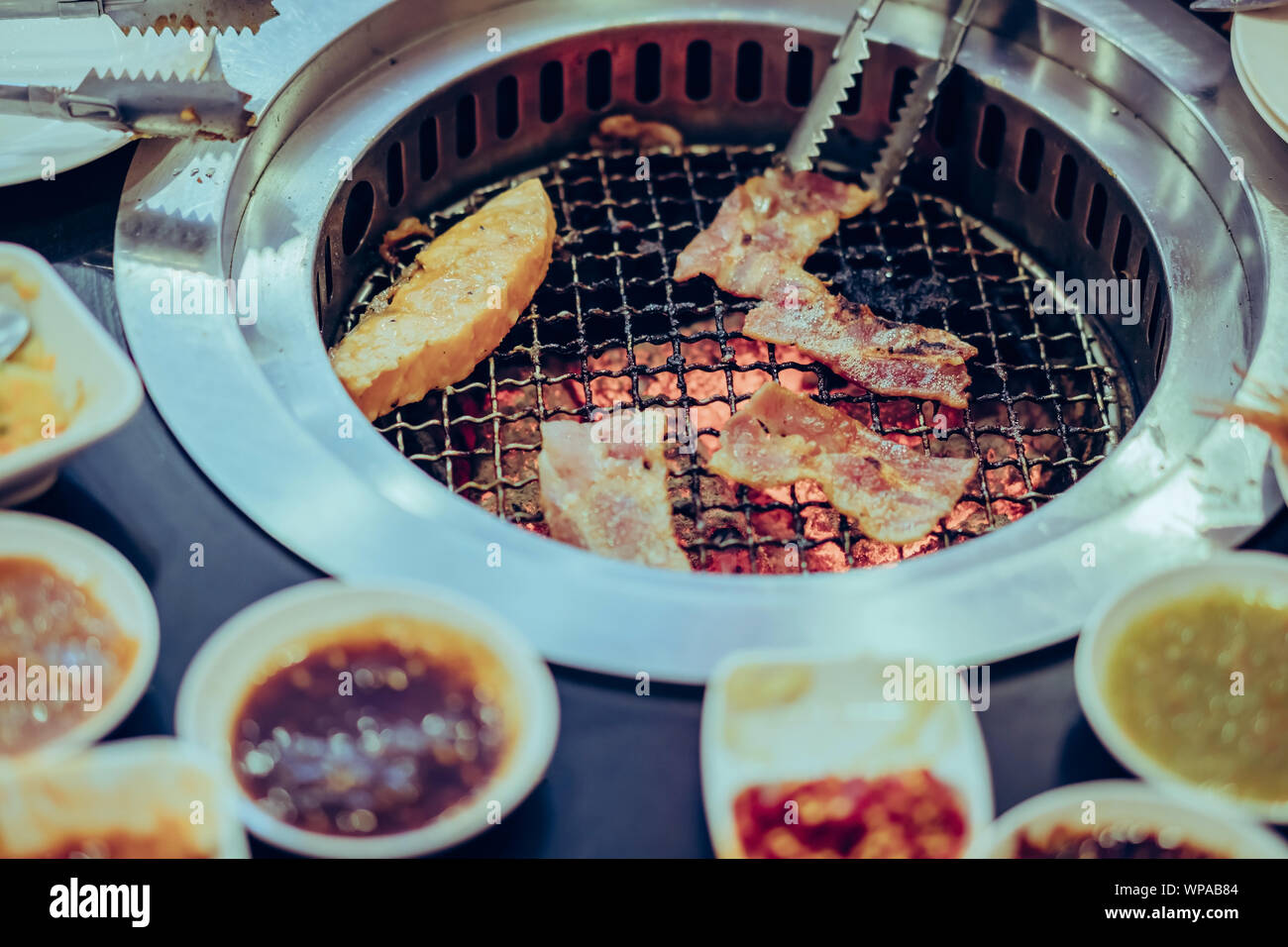 People grilling meat on a smokeless barbecue grill in a restaurant ...