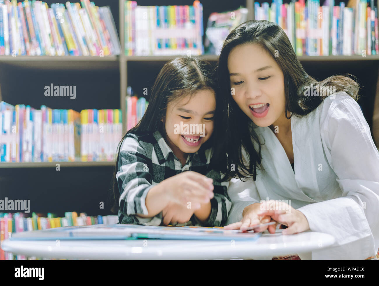 Happy mother and daughter reading book together.Mother and daughter ...