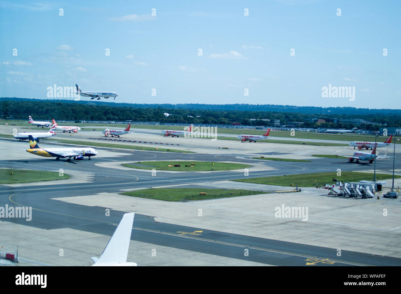 Airplanes lining up for take-off whilst a plane lands on runway Stock ...