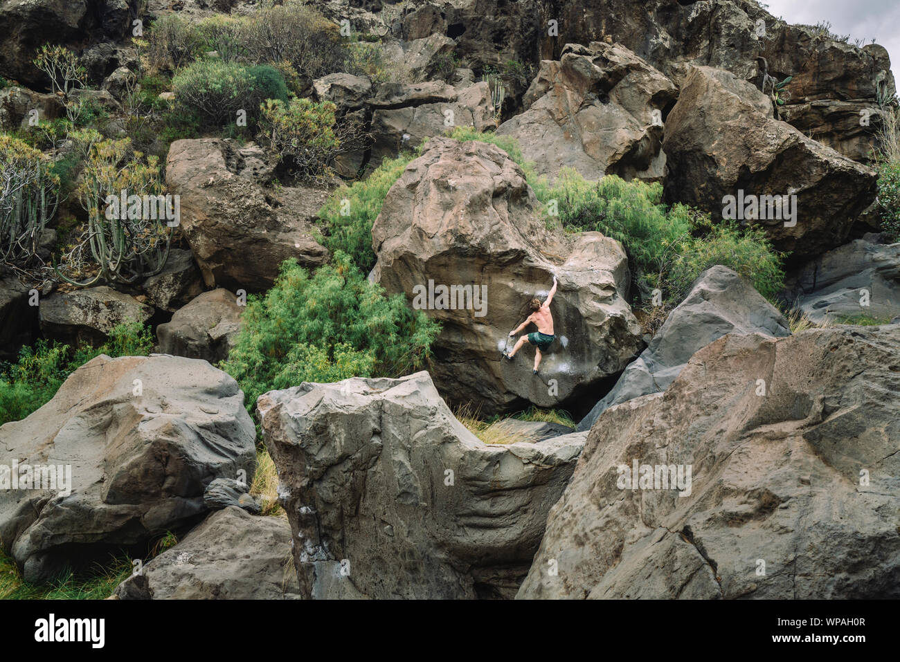 Man climbing a boulder in the middle of a volcanic landscape Stock ...