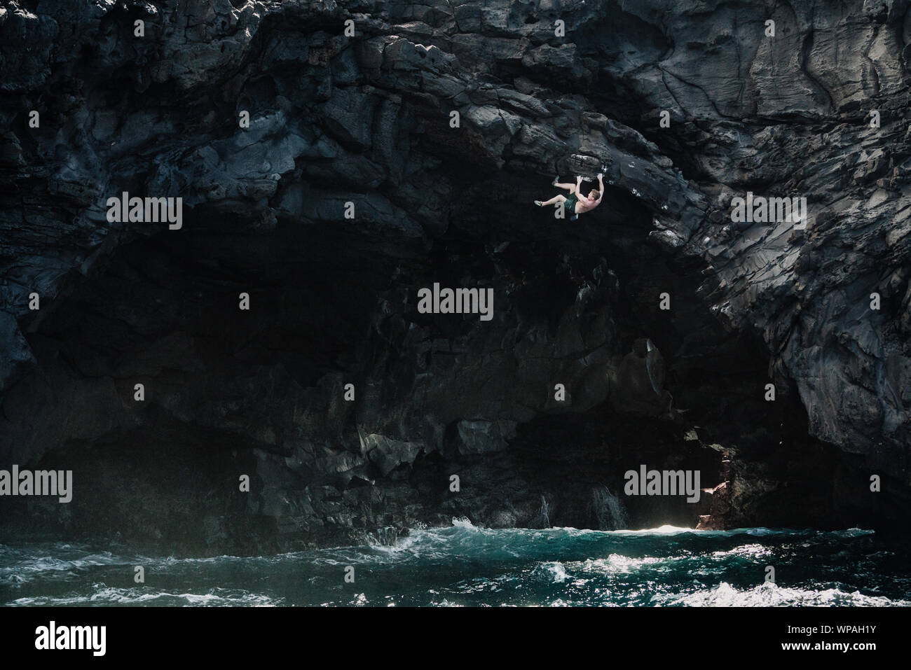 man climbing above the ocean in a volcanic cave Stock Photo - Alamy