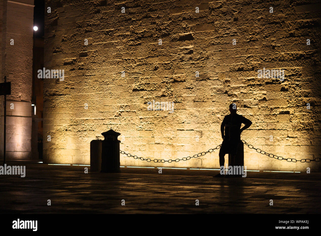 Silhouette of a man against the background of the old illuminated wall ...