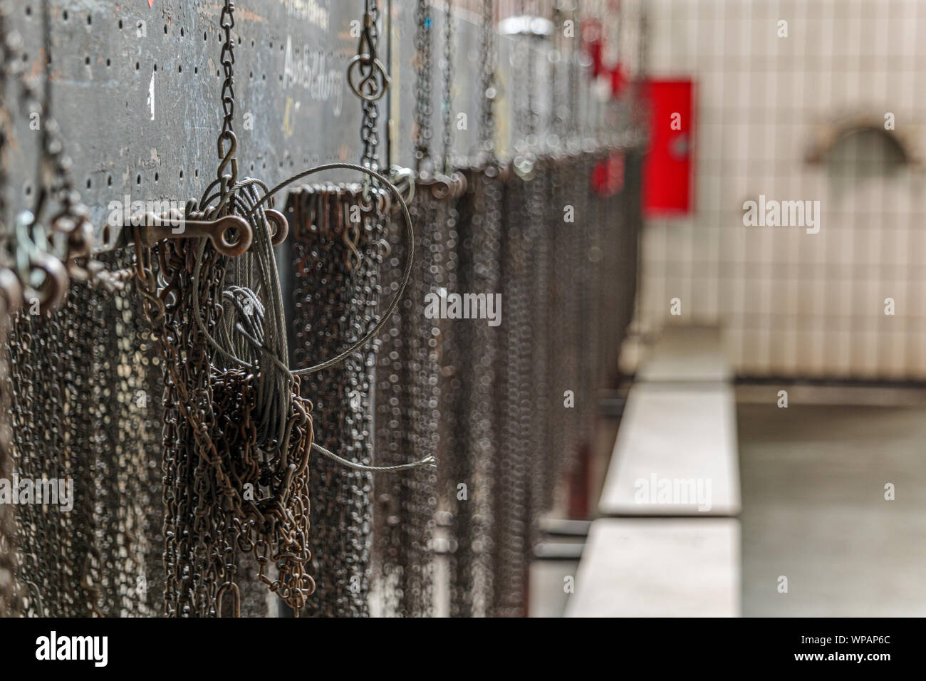 Close up group of hanging small chains inside old abandon factory or ...