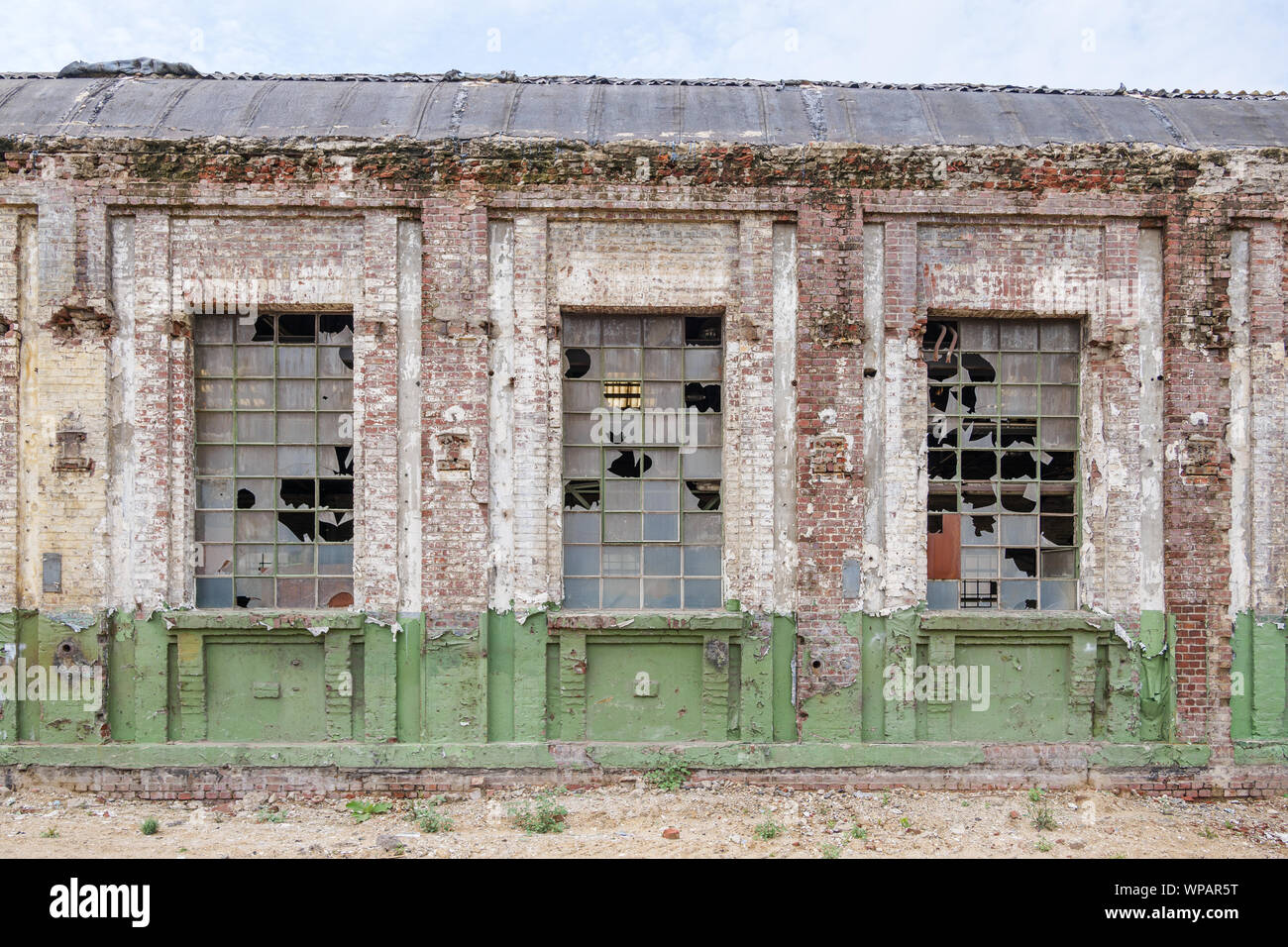 Outdoor sunny exterior view of damaged glass windows and brick wall ...