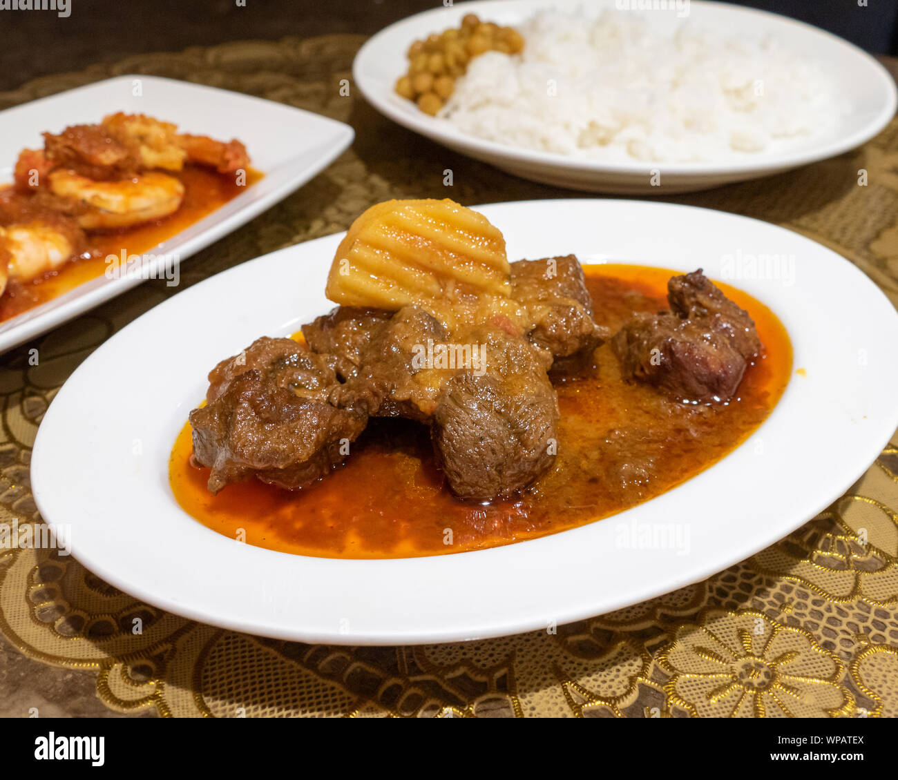 Burmese Myanmar lamb curry in plate, shrimp and dip in background Stock ...