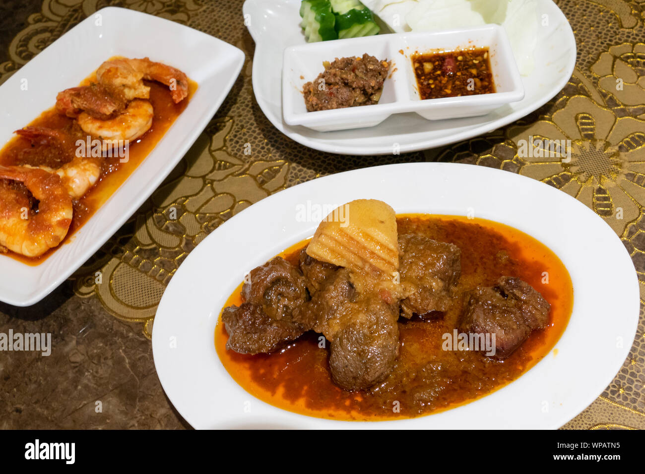 Burmese Myanmar lamb curry in plate, shrimp and dip in background Stock ...