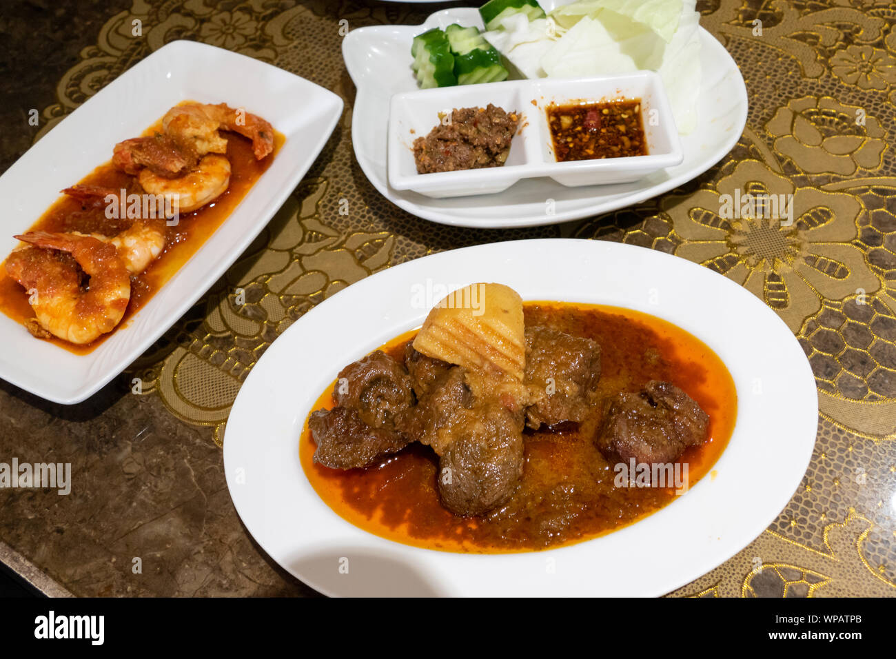 Burmese Myanmar lamb curry in plate, shrimp and dip in background Stock ...