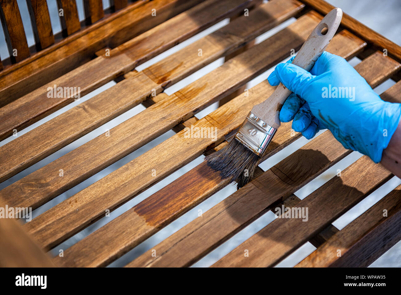 Adult carpenter craftsman painting with water-based paint the strips of ...