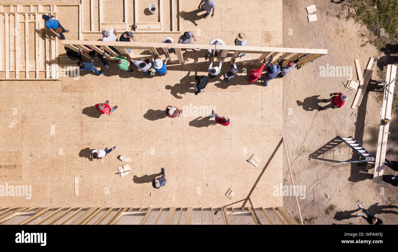 Top down view of workers raising a wall on construction of a new home ...
