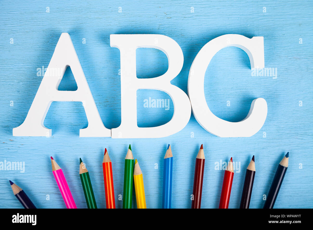 Back to school. Letters ABC and color pencils on a blue wooden ...