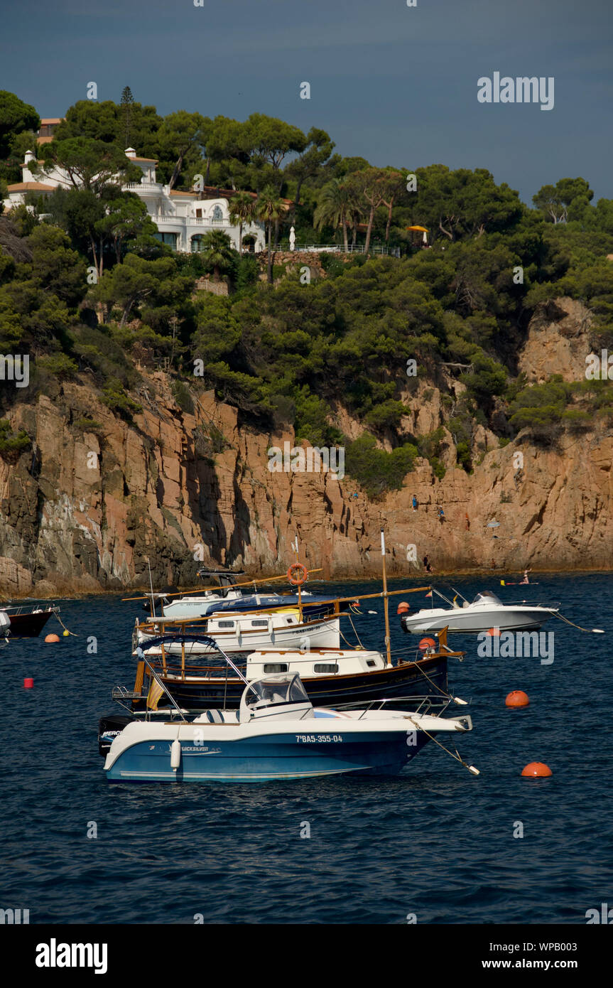 Boats on the sea below cliff top house in Tamariu Catalunya Spain Stock ...