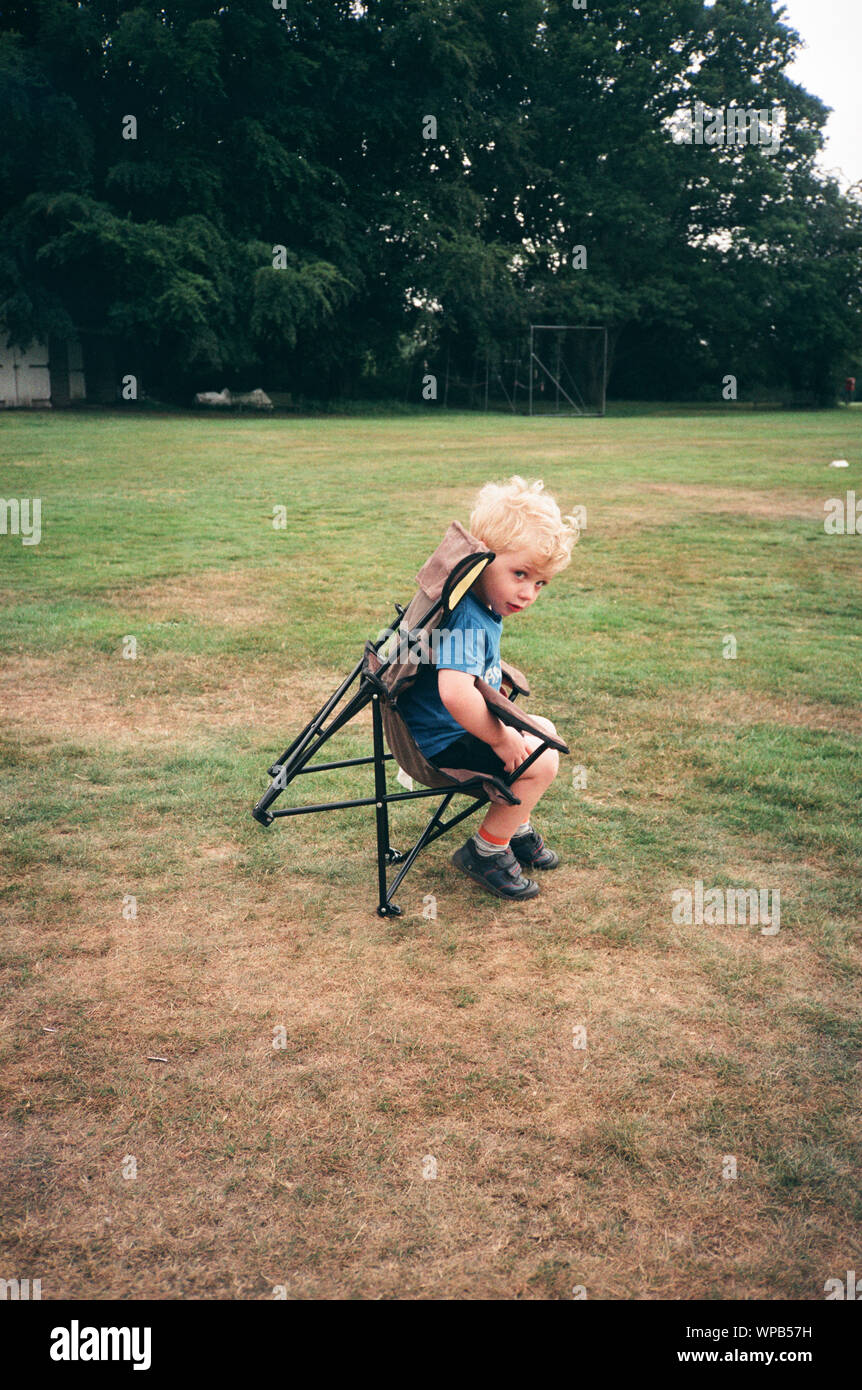 Two year old boy tipping in a fold up camping chair, Medstead. Alton ...