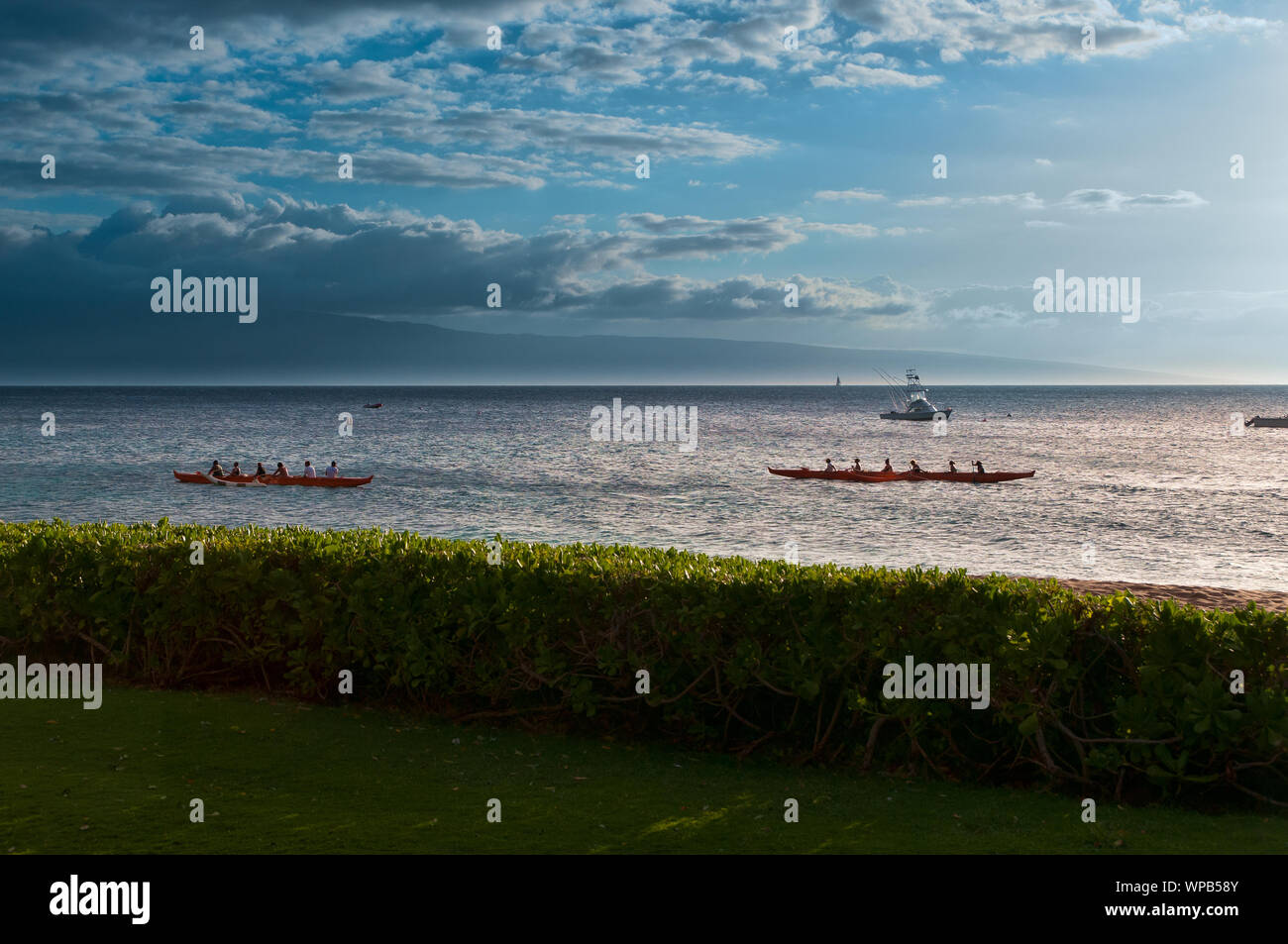 Two native Hawaiian boats rowing past at sunset on Maui, Hawaii, USA ...