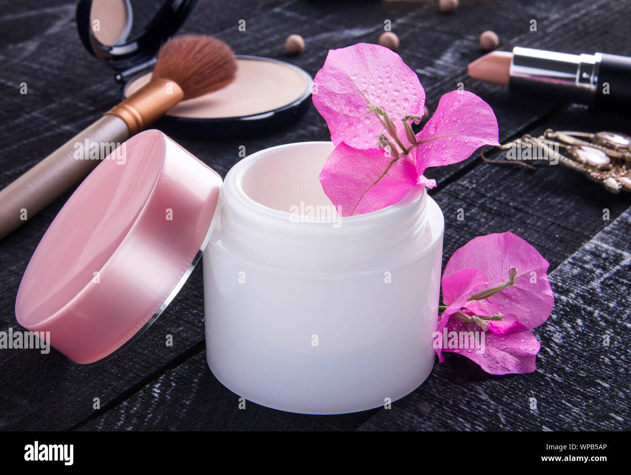 Jar of natural cream with pink flowers on black background. Organic ...