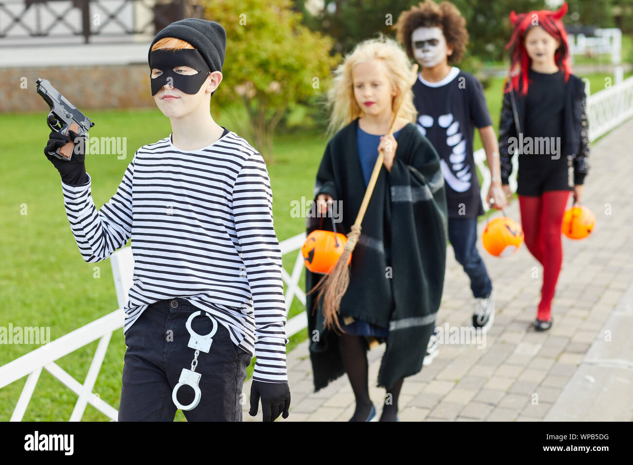Group of children wearing Halloween costumes walking in row while trick ...