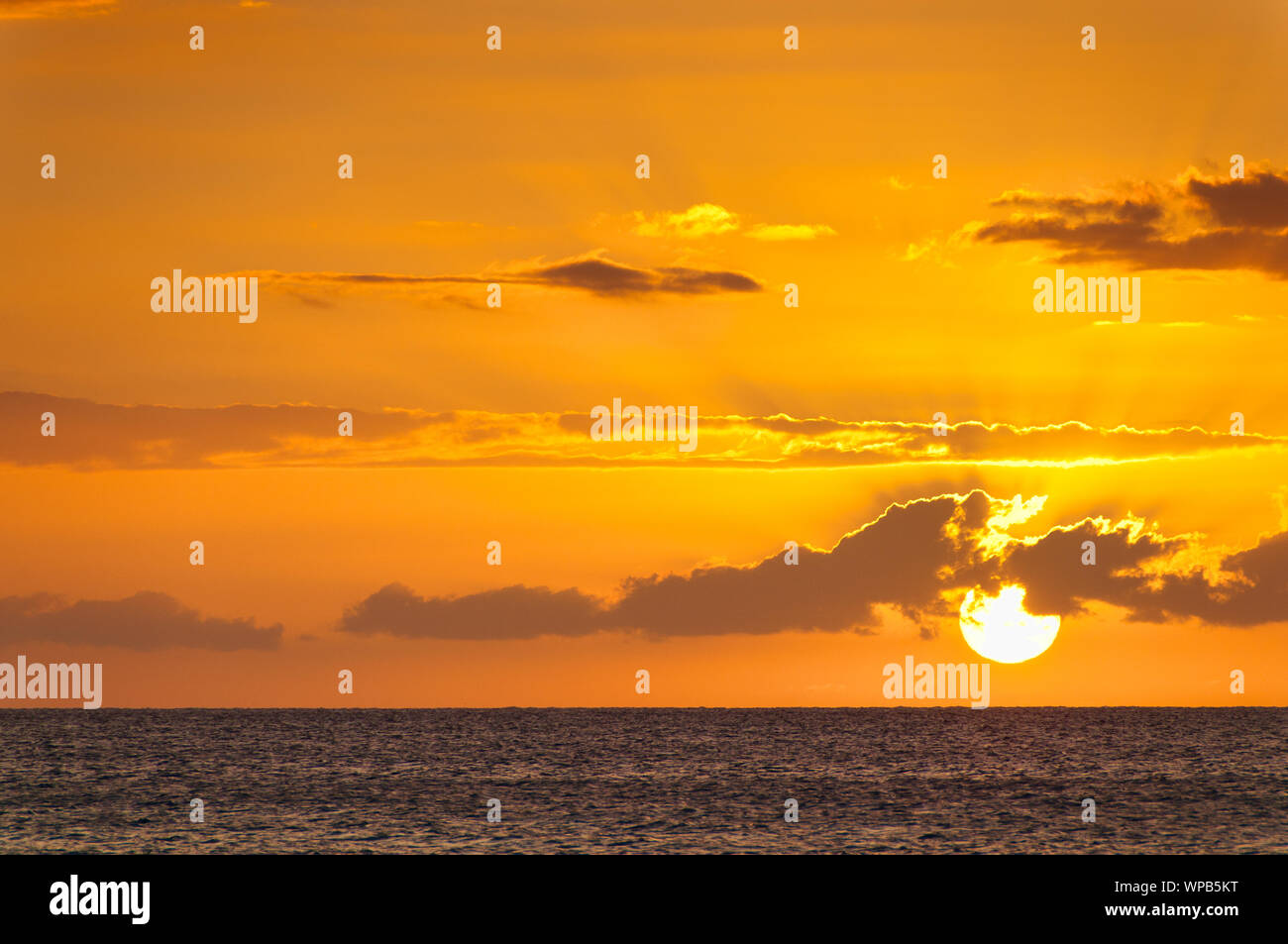 Beautiful large red sunset over the Pacific Ocean behind colorful ...