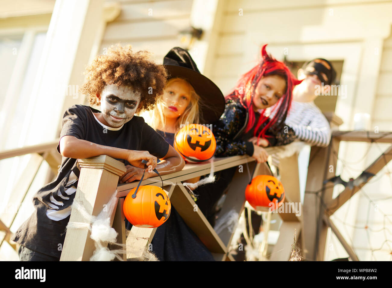 Multi-ethnic group of children wearing Halloween costumes smiling at ...