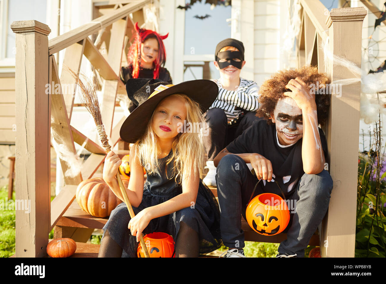 Multi-ethnic group of children wearing Halloween costumes looking at ...
