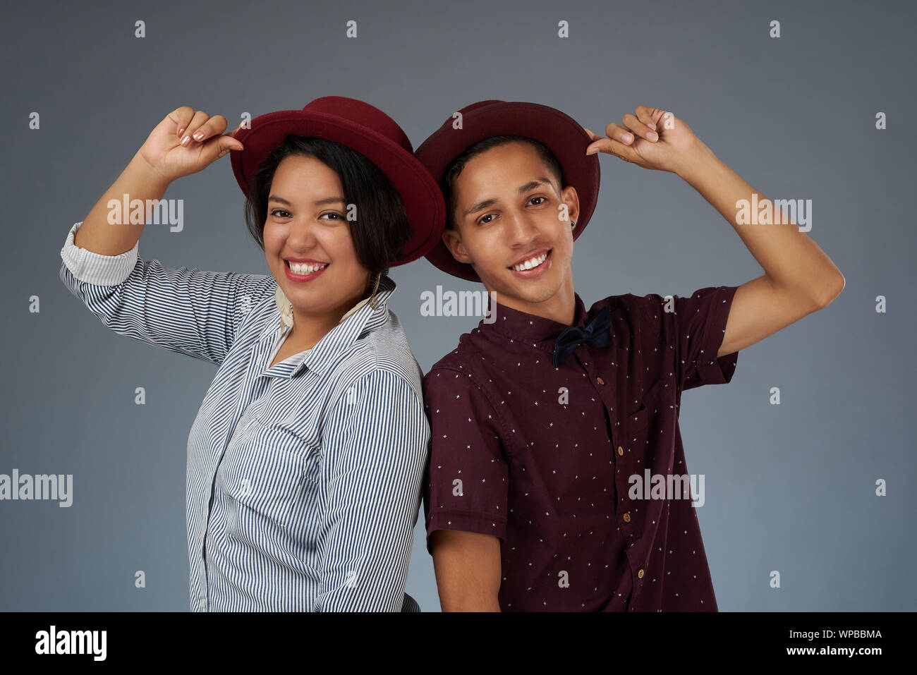 Portrait of young hipsters in red hats isolated on gray studio ...