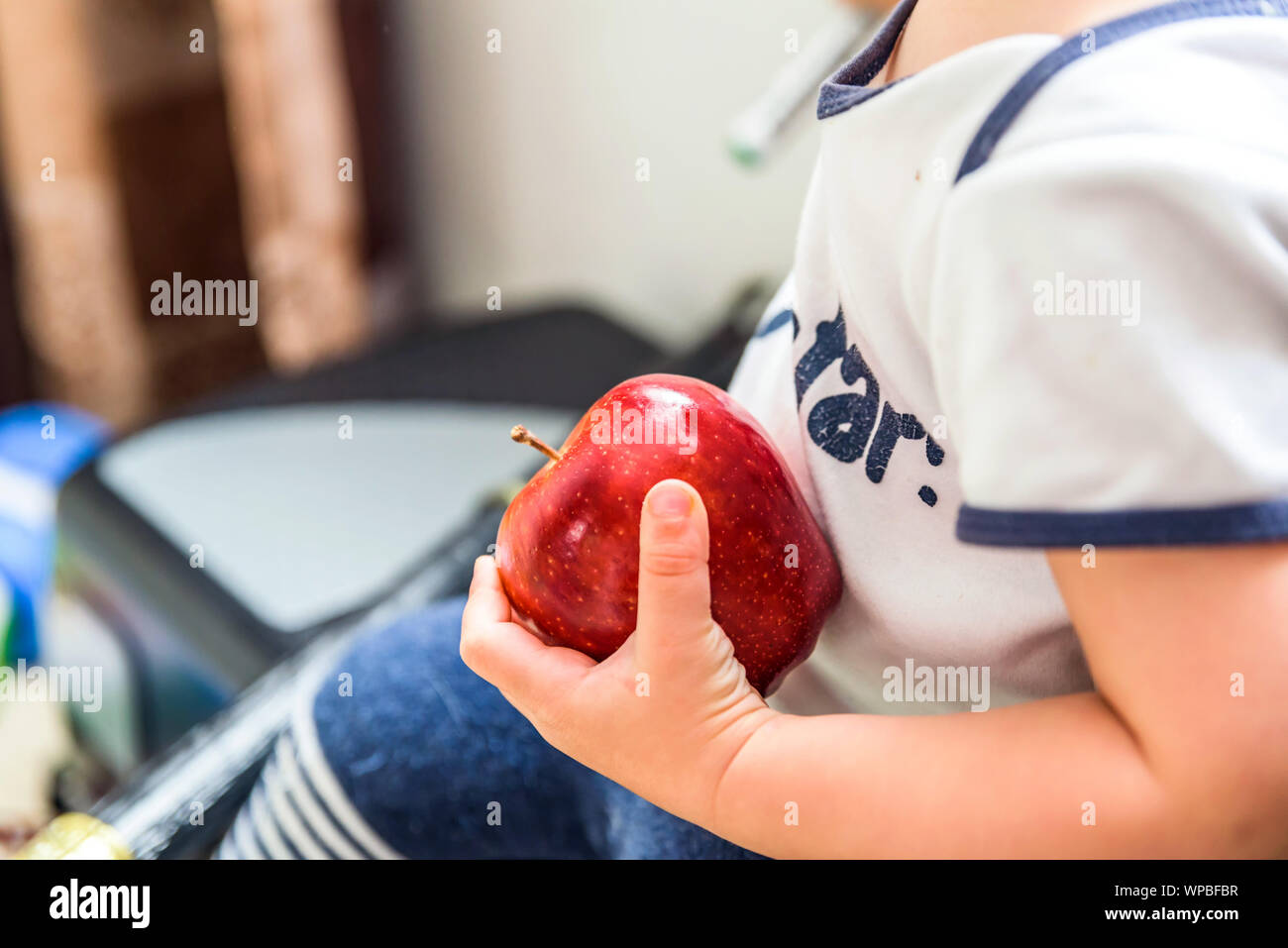 baby boy hands hold raw fresh red apple indoor. baby exploring fruit ...