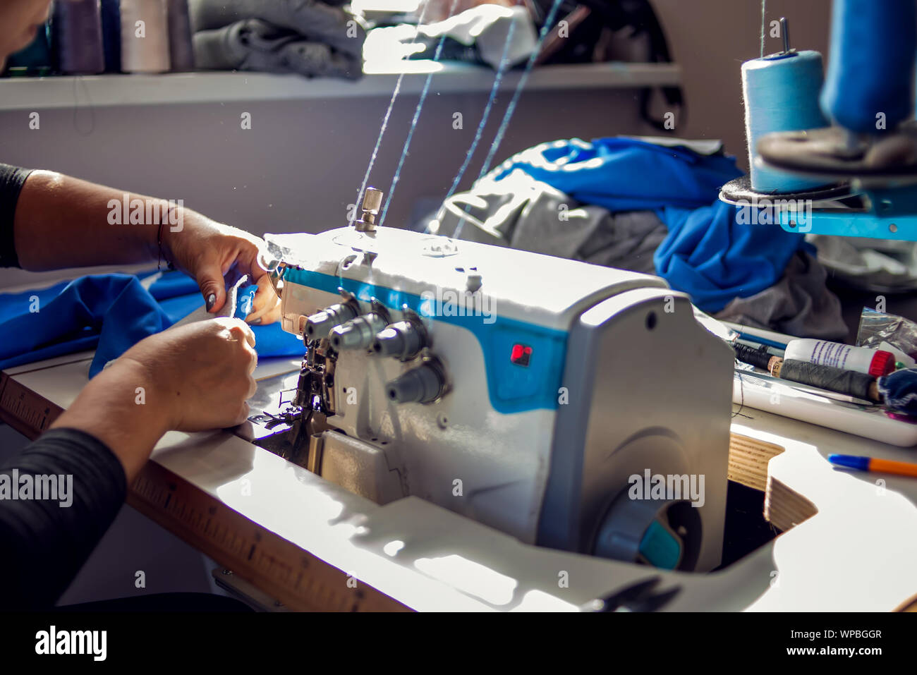 A tailor works with sewing machine. Manufacture of wearing concept ...