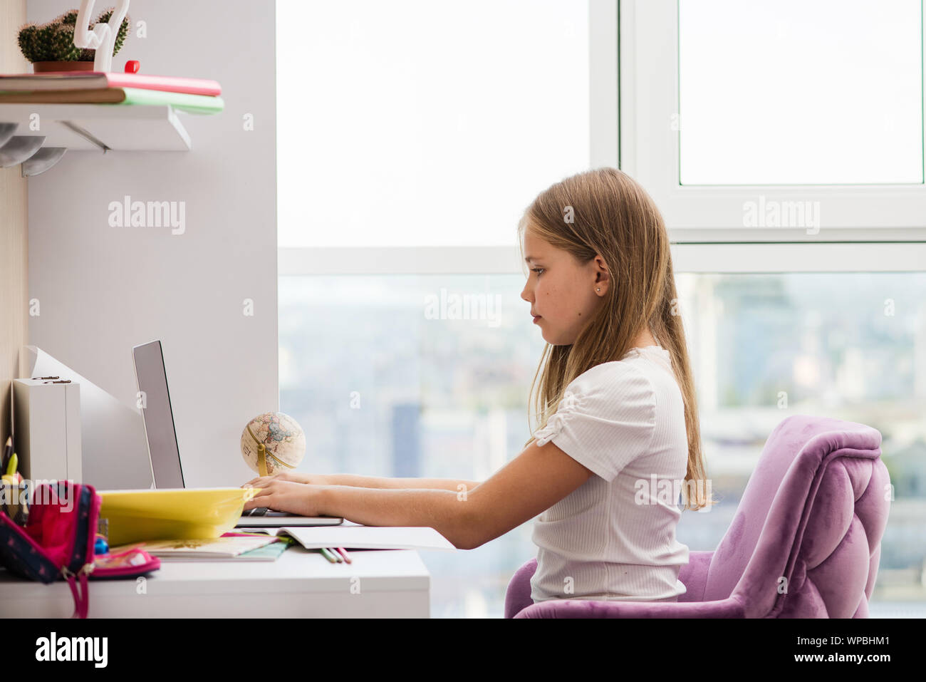 Beautiful school girl sit at desk in good posture. Large and bright ...