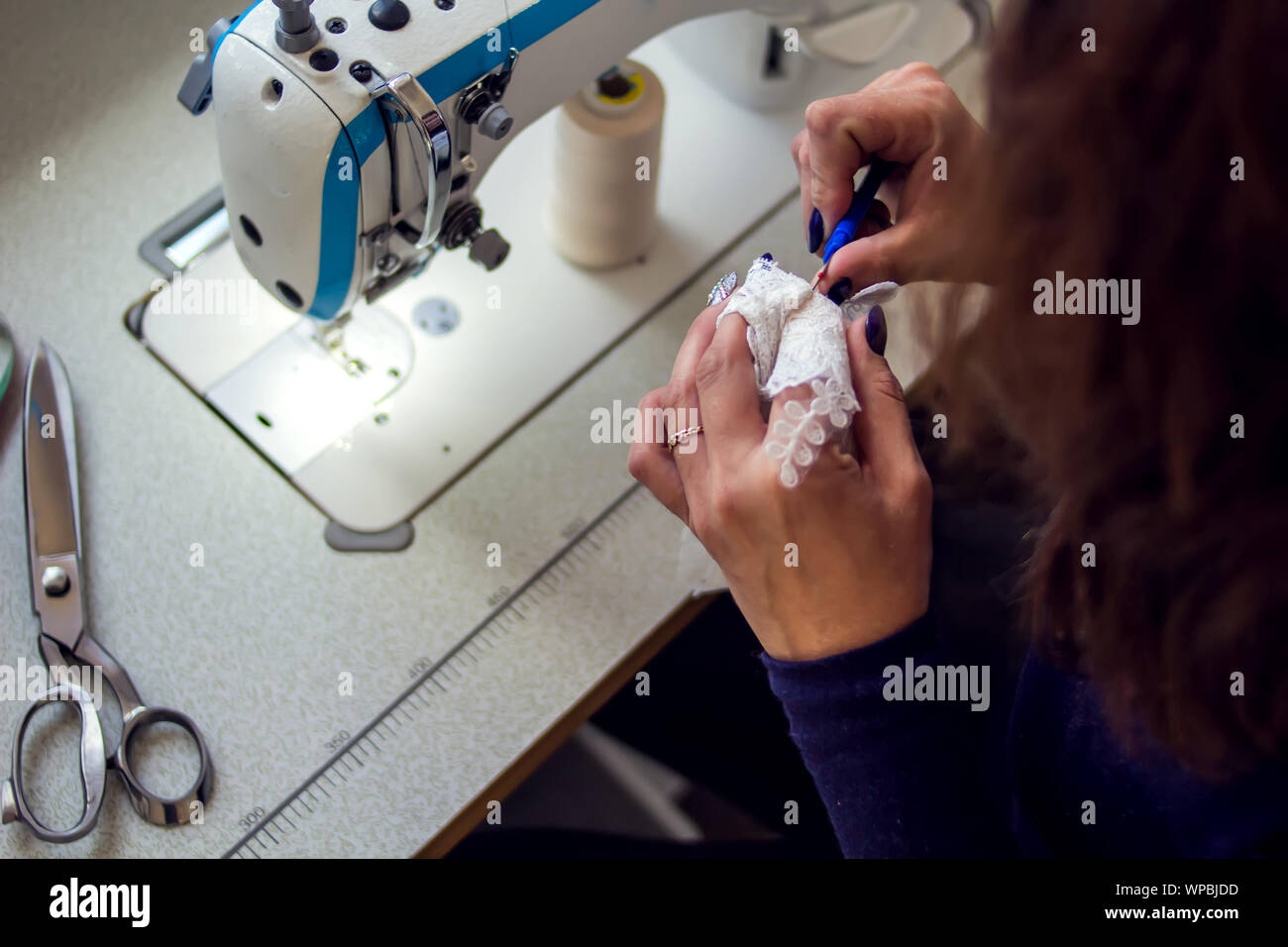 A tailor works with sewing machine. Manufacture of wearing concept ...