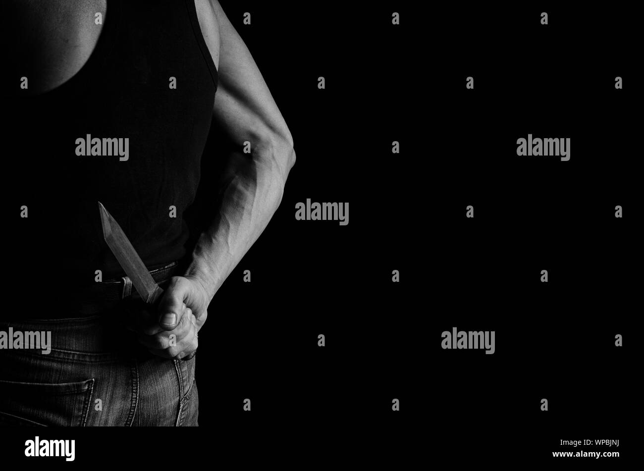 A man hides a knife behind his back in black and white Stock Photo - Alamy