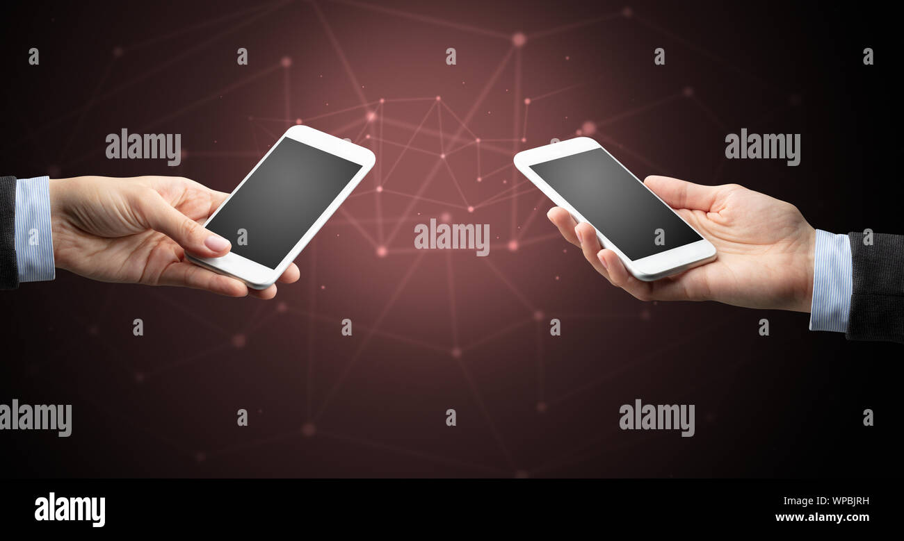 Close up of two hands holding smartphones to each other, wireless ...