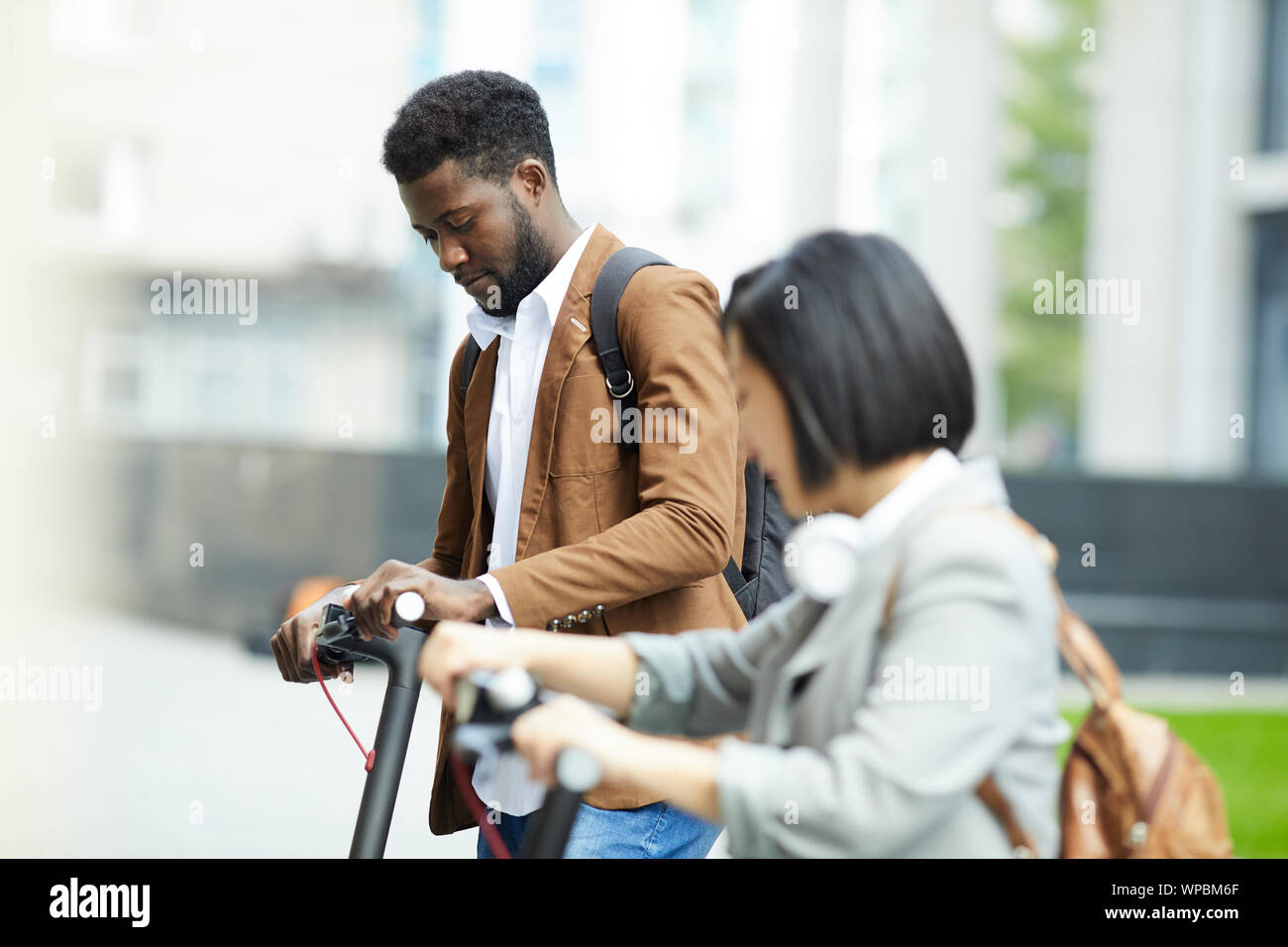 Side view portrait of two people riding electric scooters in city ...