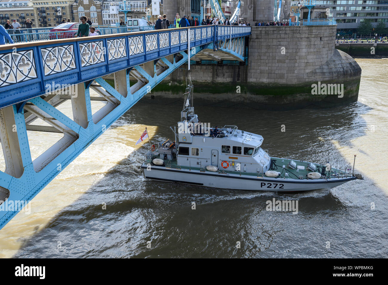 A small military boat of the Royal Navy passing under Tower Bridge ...