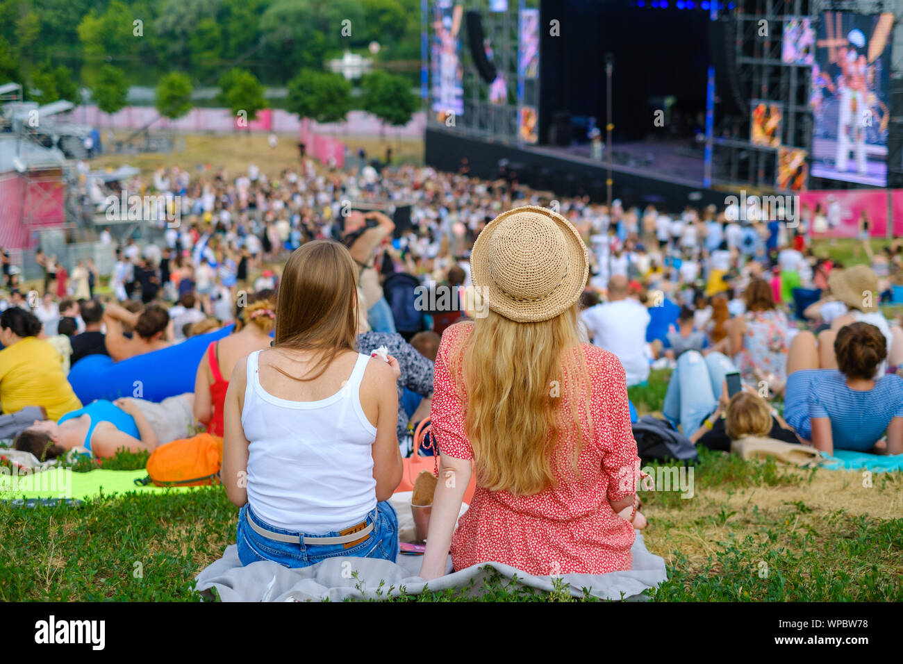 Girls friends watching concert at open air music festival, back view ...
