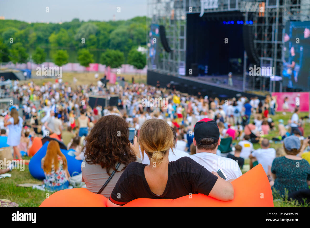 Friends watching concert at open air music festival, back view, stage ...